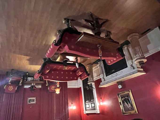 Furniture clings impossibly to the ceiling in this inverted room, creating a disorienting experience that challenges your sense of gravity.