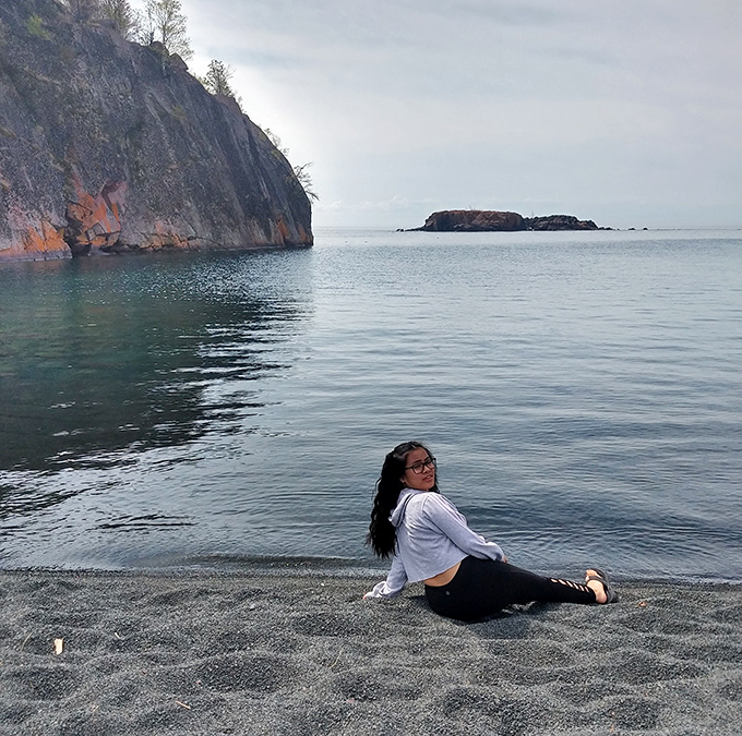 A moment of peaceful contemplation on the dark sand, where the only sounds are waves and the occasional cry of gulls overhead.