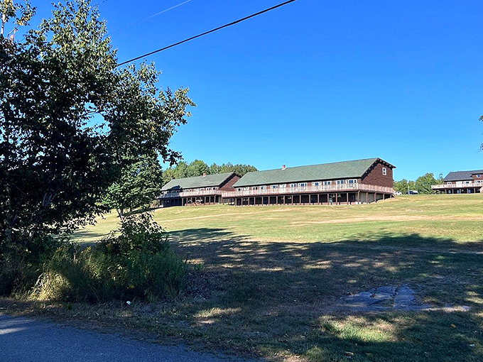 A quiet stretch of countryside where wide open fields meet rustic buildings—simple, peaceful, and wrapped in the calm of a clear blue sky.
