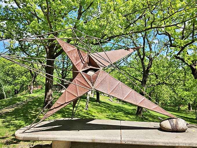 Modern sculpture spreads its angular wings against a backdrop of trees, art and nature in perfect harmony.