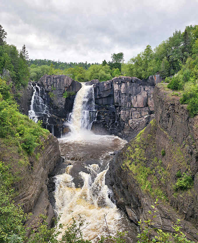 The magnificent High Falls at Grand Portage plunges dramatically between rocky cliffs, showcasing Minnesota's tallest waterfall in all its thundering glory.