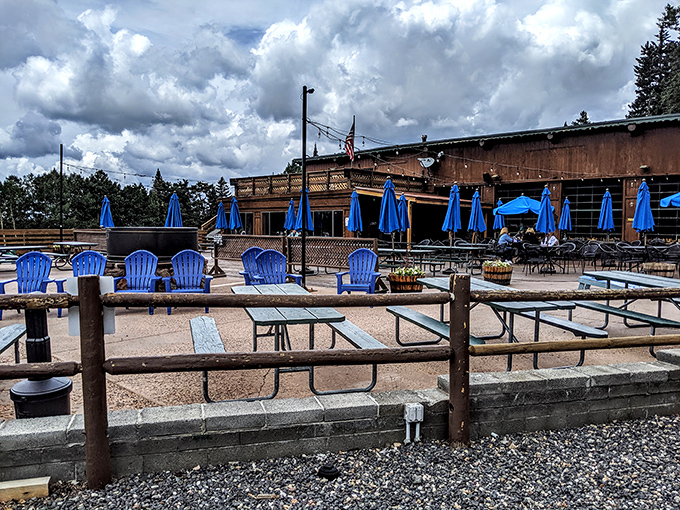 The rustic outdoor seating area at Agassiz Lodge offers a perfect summer escape with blue Adirondack chairs and mountain views.