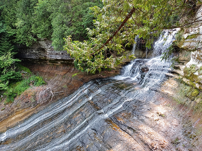 Sunlight dances across the broad, sloping cascade of Laughing Whitefish Falls, highlighting water patterns carved over thousands of years.