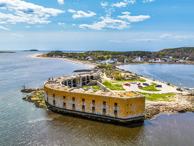 Fort Popham's historic stone structure guards Phippsburg's coastline, with a lighthouse and bridge visible in the distance.