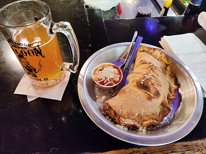 A frosty mug of local brew accompanies a calzone that looks like it's trying to escape the plate.