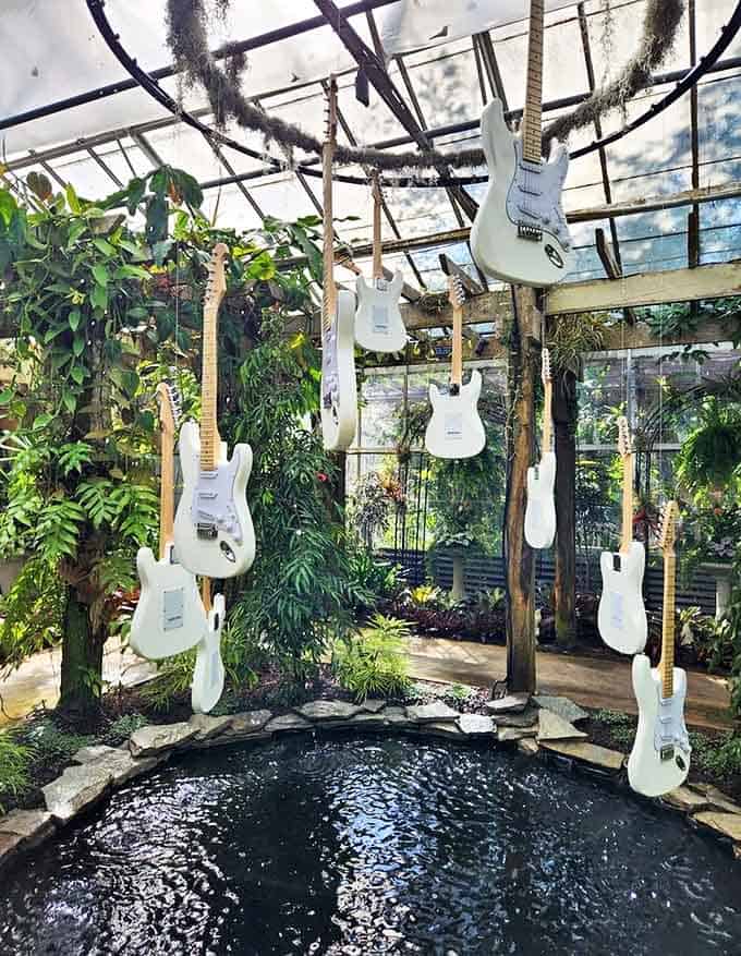 Electric guitars hang like exotic fruit in this greenhouse installation, where music and botany create an unexpected harmony.