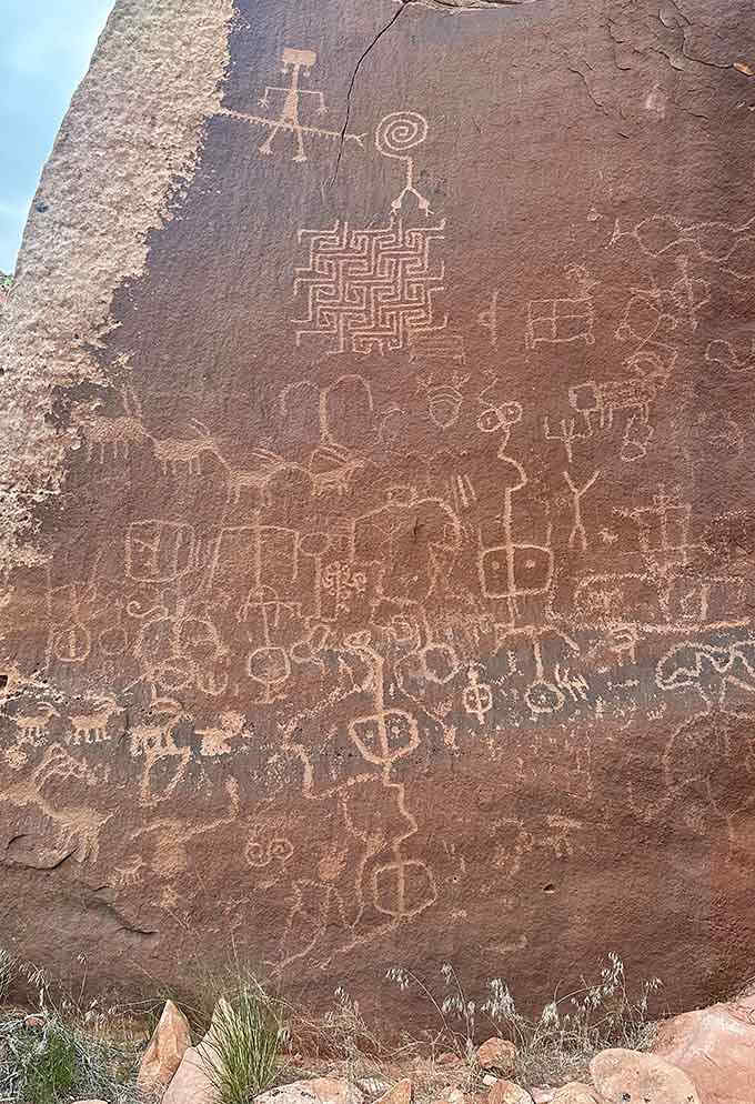 Intricate geometric patterns and figures cover the rock face like an ancient comic book frozen in stone.
