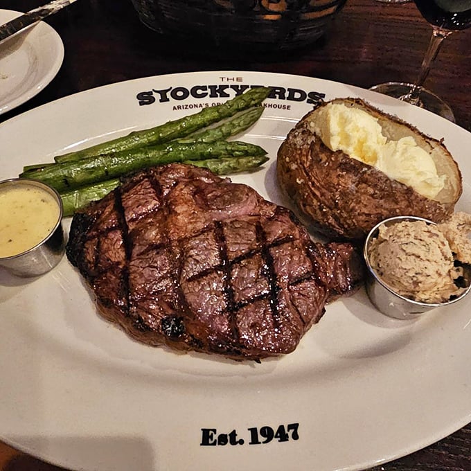 A perfectly grilled ribeye shares the spotlight with asparagus spears and a baked potato that's practically begging to be buttered.