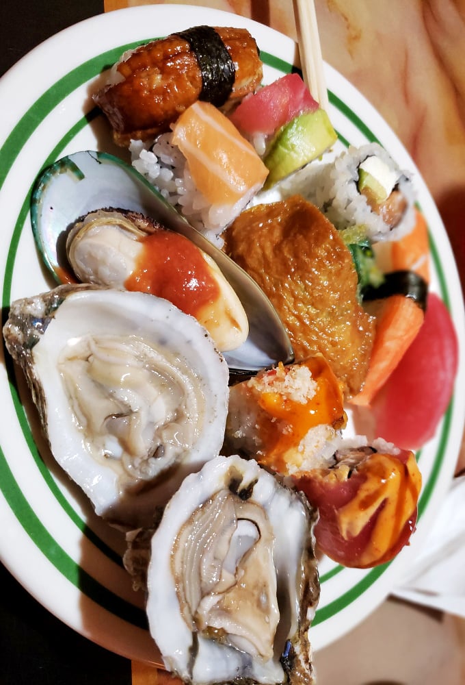 Fresh oysters and sushi rolls share plate space, proving that seafood options extend well beyond what you'd expect at a standard buffet.