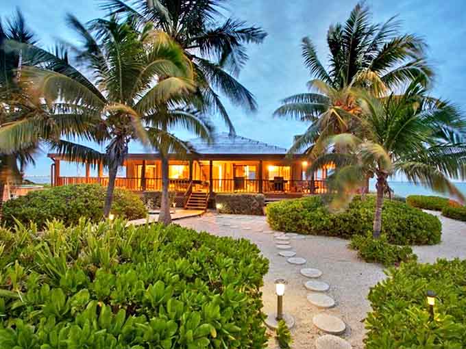 As evening embraces the island, warm lights from the villa create a beacon of comfort amid the surrounding sea of darkness.