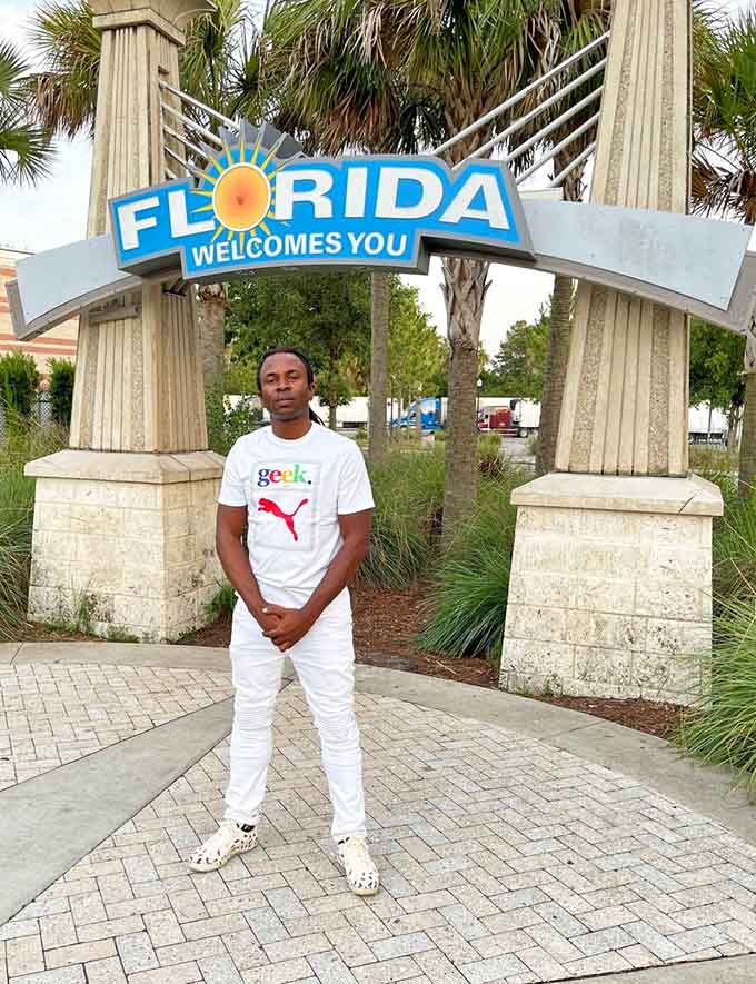 Visitors strike their best poses beneath the archway, joining the grand tradition of documenting the exact moment vacation officially started.