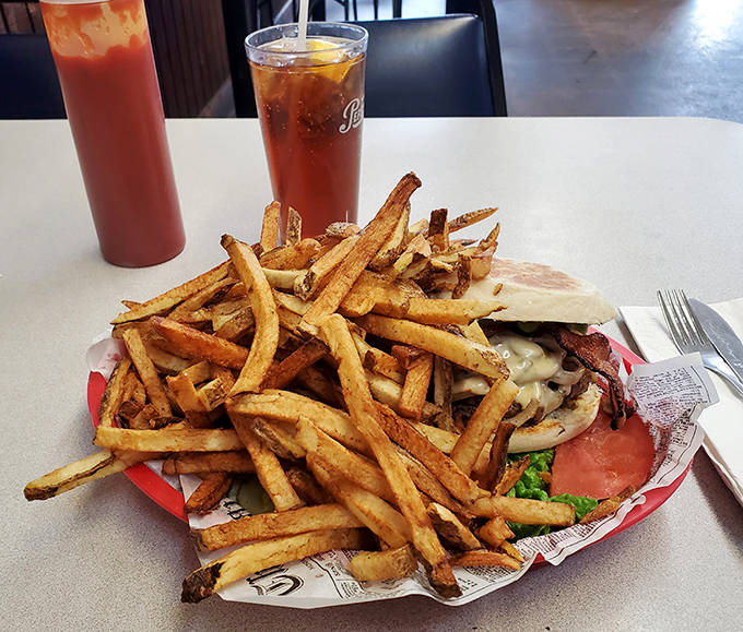 Mountains of hand-cut fries surround a burger masterpiece, with sweet tea standing by to wash down this magnificent feast.