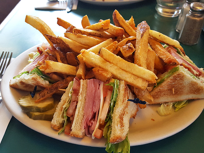 This club sandwich towers like a delicious skyscraper, packed with turkey, ham, bacon, and enough fries to fuel a small army or one very hungry person.