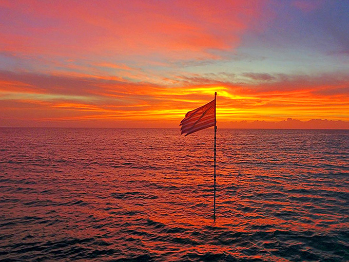 Dawn breaks over the shipwreck's flag, a patriotic sentinel rising from the deep. Morning glory with extra saltwater.