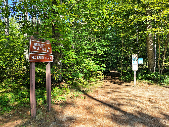 The trailhead sign stands like a promise of adventure, pointing the way to Michigan's most scenic 19.2-mile nature experience.