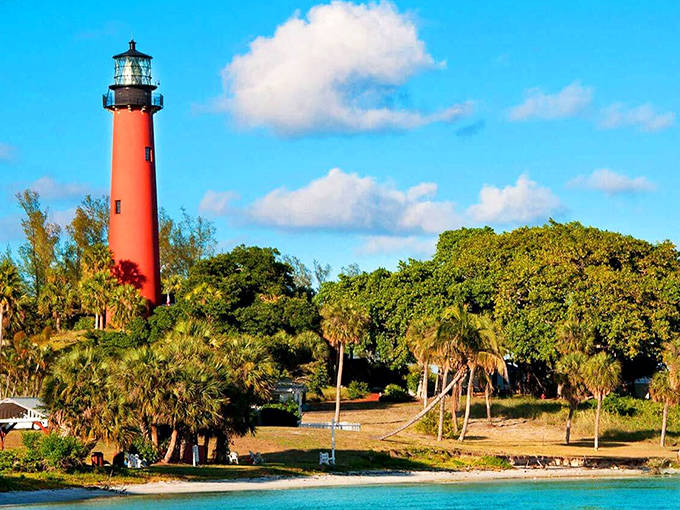 The brick-red Jupiter Inlet Lighthouse stands tall above palm trees and waterways. Its position offers spectacular views of the inlet and Atlantic Ocean.