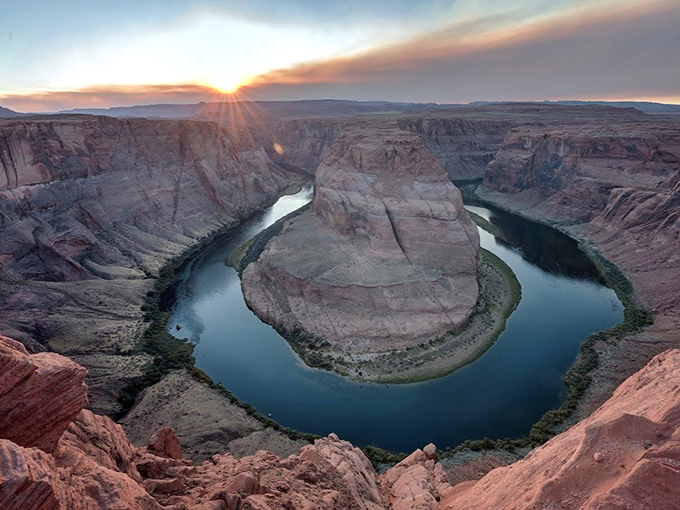 The Colorado River makes its famous horseshoe turn, carving a perfect curve through red sandstone cliffs in this breathtaking aerial view.
