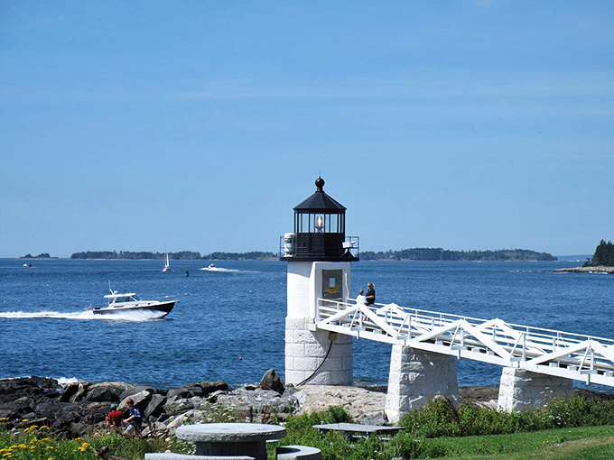 Port Clyde's lighthouse stands sentinel at the harbor entrance, with its classic black and white design guiding mariners safely home.