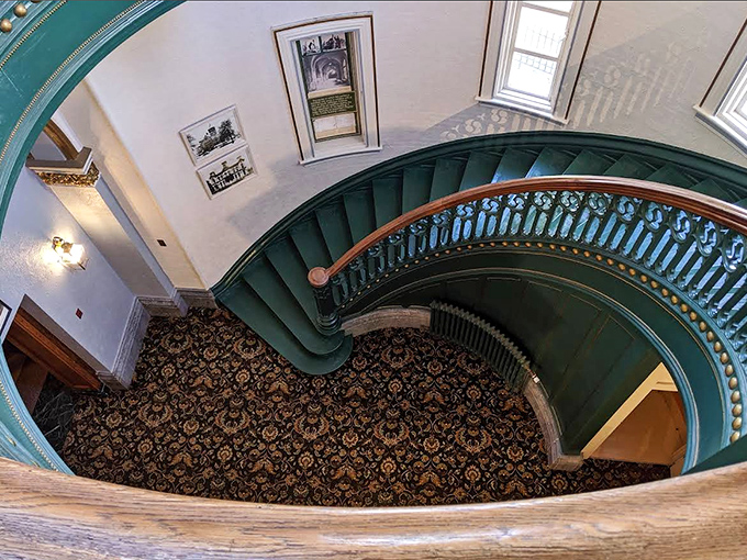 The museum's stunning spiral staircase curves gracefully downward, its green steps and ornate railings showcasing the architectural splendor of this Michigan castle.