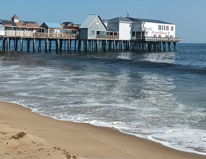Another view of the historic pier at Old Orchard Beach with gentle waves lapping at the sandy shore, inviting visitors to enjoy classic Maine beach fun.