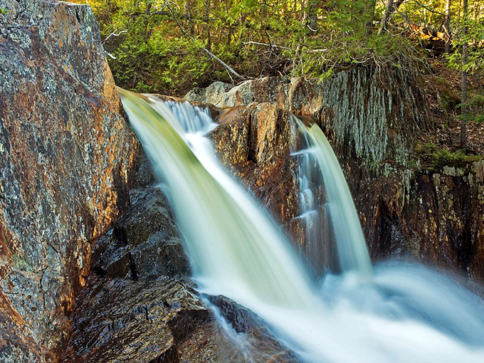 Golden-orange rocks provide a stunning backdrop for the crystal-clear pools at the base of Smalls Falls.