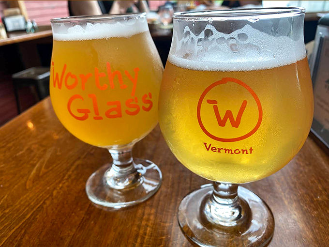 Two golden glasses of Vermont craft beer catch the light, promising refreshment that pairs perfectly with the wood-fired flavors of Worthy's menu.