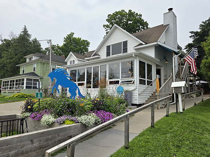 The Blue Horse Beach Cafe greets visitors with its whimsical equine guardian and flower gardens that frame lake views.