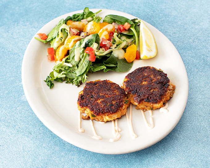 Golden-brown perfection with a crispy exterior giving way to sweet, flaky crab meat &ndash; minimal filler, maximum flavor, served with a fresh side salad.