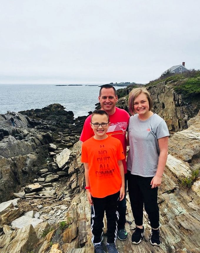 The image shows visitors enjoying the spectacular coastal views that make this trail worth every careful step.