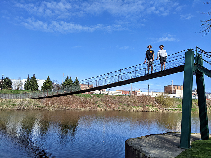 Two adventurers pause mid-bridge, perhaps contemplating life's mysteries or just enjoying the gentle rocking motion beneath their feet.