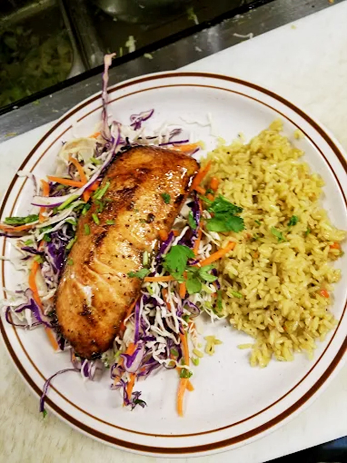 Perfectly grilled salmon rests on a bed of colorful slaw and herb-infused rice &ndash; proof that Vermont restaurants can nail seafood with surprising finesse.