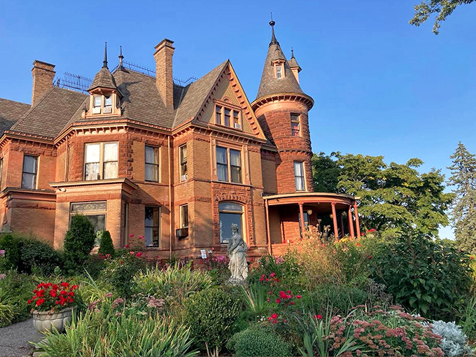Henderson Castle's red stone exterior and dramatic turret create a striking silhouette against the Kalamazoo sky, now welcoming guests as a bed and breakfast.