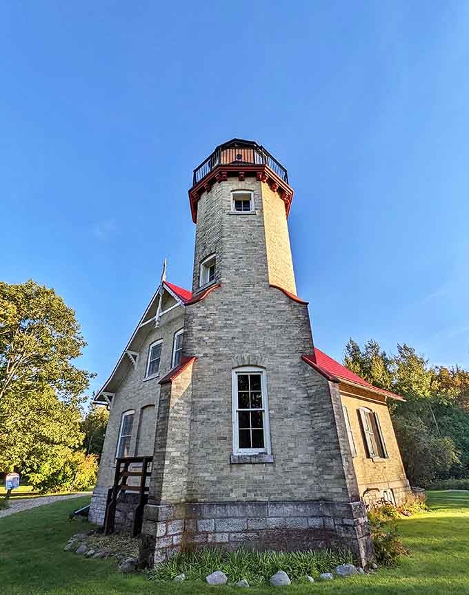 The stone lighthouse stands proud against blue skies, its weathered walls telling tales of storms weathered and ships guided home.