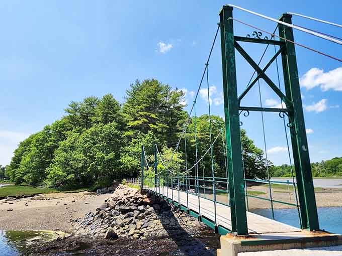The green suspension bridge stretches across calm waters, inviting visitors to experience its famous bouncy walk and scenic views.