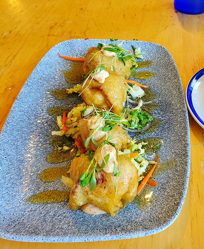 Bacon-wrapped scallops on a sea-blue plate &ndash; proof that sometimes the simplest combinations are culinary genius. The microgreens add color and conscience.