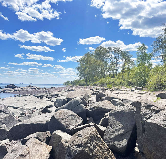 Massive rocks create natural breakwaters along the shore, their surfaces telling geological stories spanning billions of years.