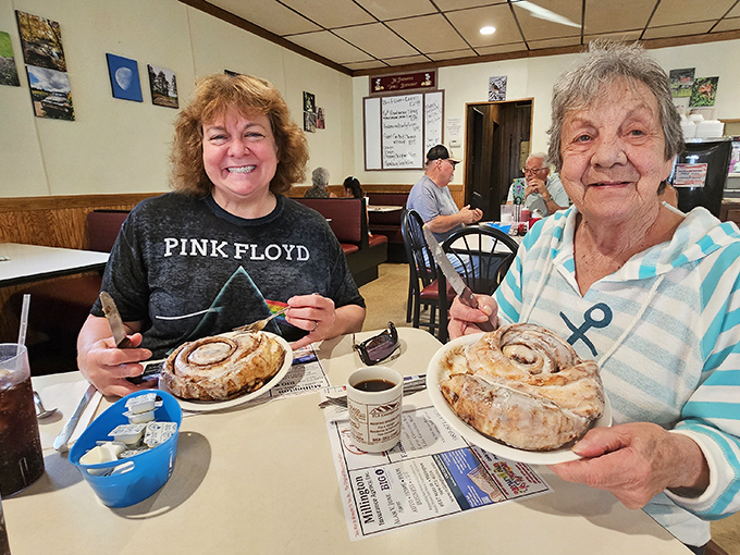 Happy diners showing off their cinnamon roll conquests &ndash; these pastries aren't just eaten, they're experienced and celebrated.