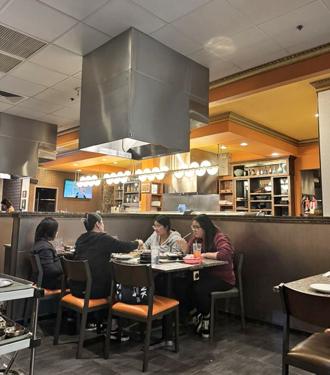 The dining room hums with conversation as patrons gather around tables, the shared experience of tabletop cooking creating instant connections and memorable meals.