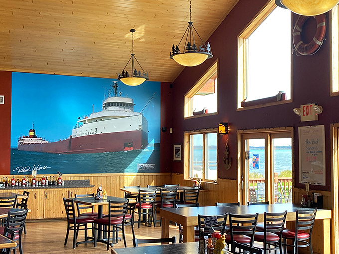 Sunlight streams through tall windows onto wooden tables while a Great Lakes freighter stands sentinel on the wall – dining room or maritime museum? Both!