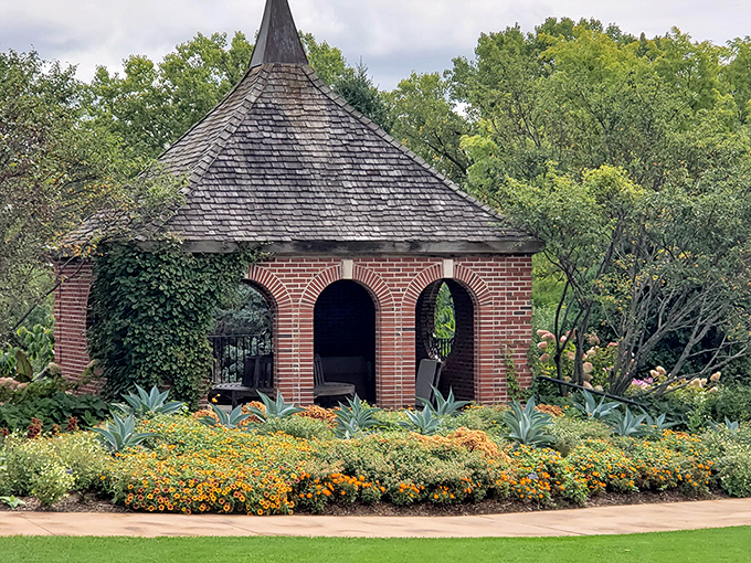The brick gazebo at Green Bay Botanical Garden sits surrounded by vibrant blooms, offering a shaded retreat that whispers "bring a book and stay awhile."