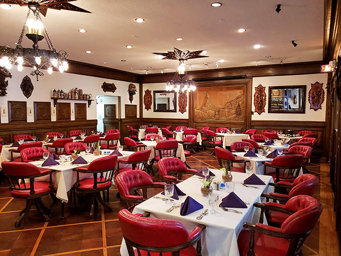 The main dining room balances formality with comfort &ndash; red chairs pop against white tablecloths while wood accents add warmth to this classic American dining experience.