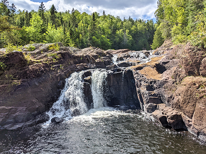 Judge Magney State Park's waterfall splits dramatically around ancient rock, half continuing downstream, half vanishing mysteriously underground.