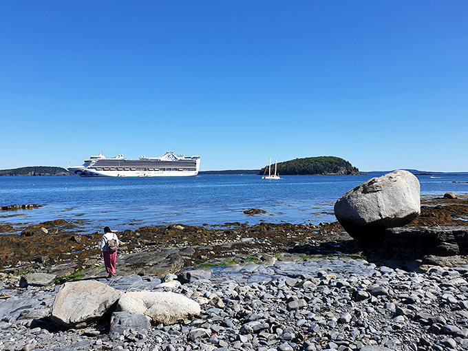 Crystal clear waters reveal Maine's characteristic rocky shoreline, with distant islands creating a layered landscape of blues and greens.