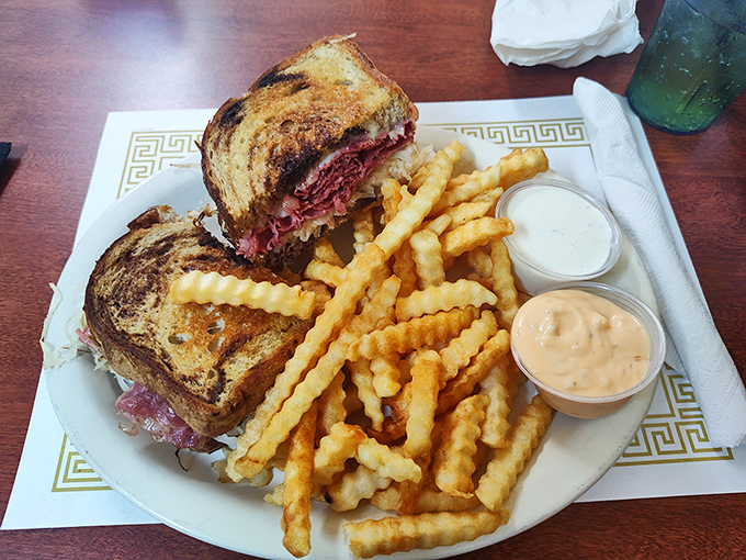 The pastrami sandwich arrives with a mountain of meat between rye, flanked by crinkle-cut fries standing at attention like delicious soldiers.