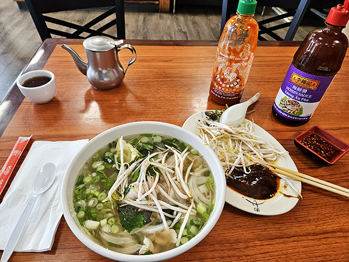 A classic bowl of pho arrives with all the fixings &ndash; bean sprouts, herbs, and lime &ndash; ready for customization.