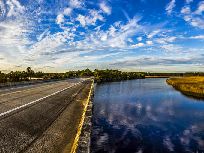 Golden-hour light warms this bridge, as clouds and water reflect each other beautifully.