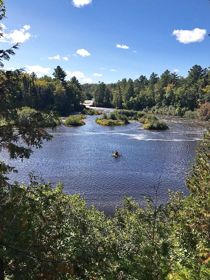 A panoramic view where Michigan's pristine wilderness creates nature's perfect postcard &ndash; tranquil waters embracing verdant islands while evergreens stand guard under an impossibly blue sky.

