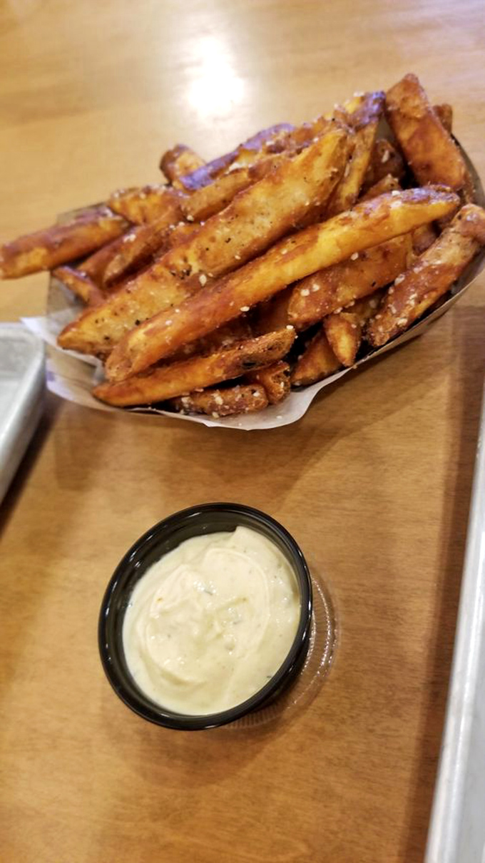 Hand-cut truffle fries with garlic aioli prove that The Toasted Pickle's culinary prowess extends well beyond their namesake ingredient.