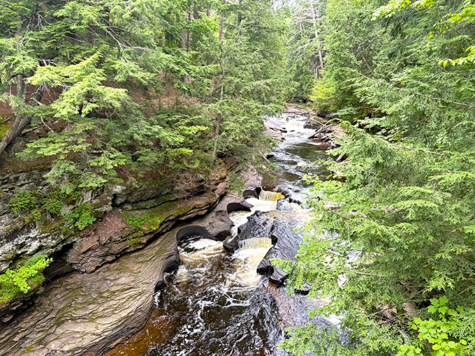 River potholes tell geological stories spanning millennia, where patient water and spinning stones have carved perfect circles into ancient bedrock.