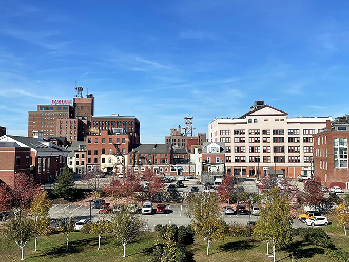 A quiet downtown moment under wide blue skies, where brick buildings, autumn trees, and everyday life come together in simple harmony.